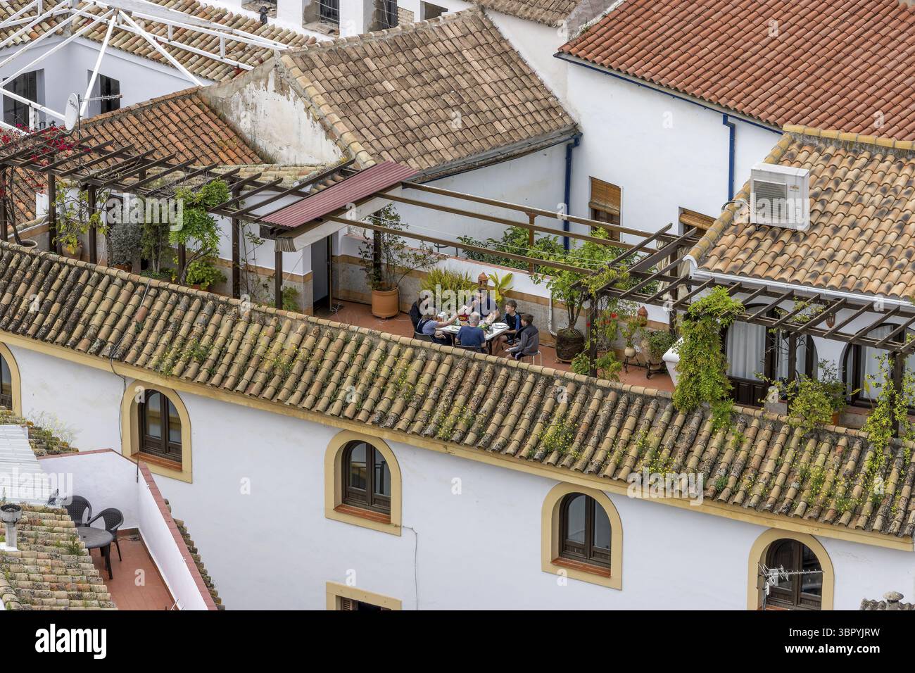 A roof terrace with roofs and a group of people at a table in Juderia ...