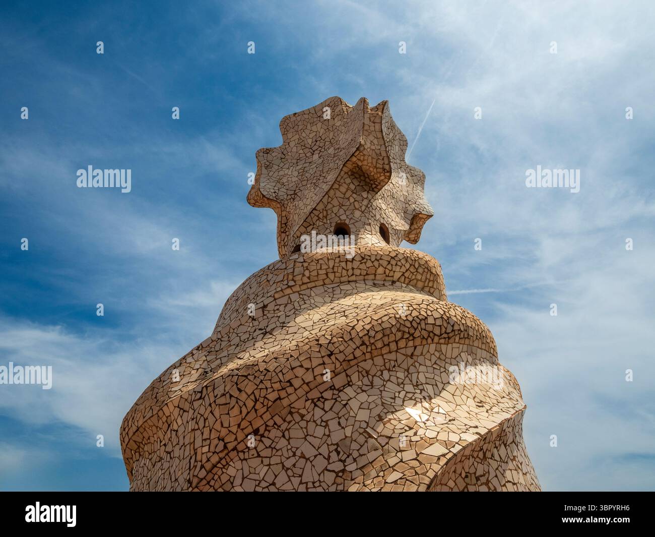 Looking up at a twisted, sculptural chimney covered in white 'trencadís ...