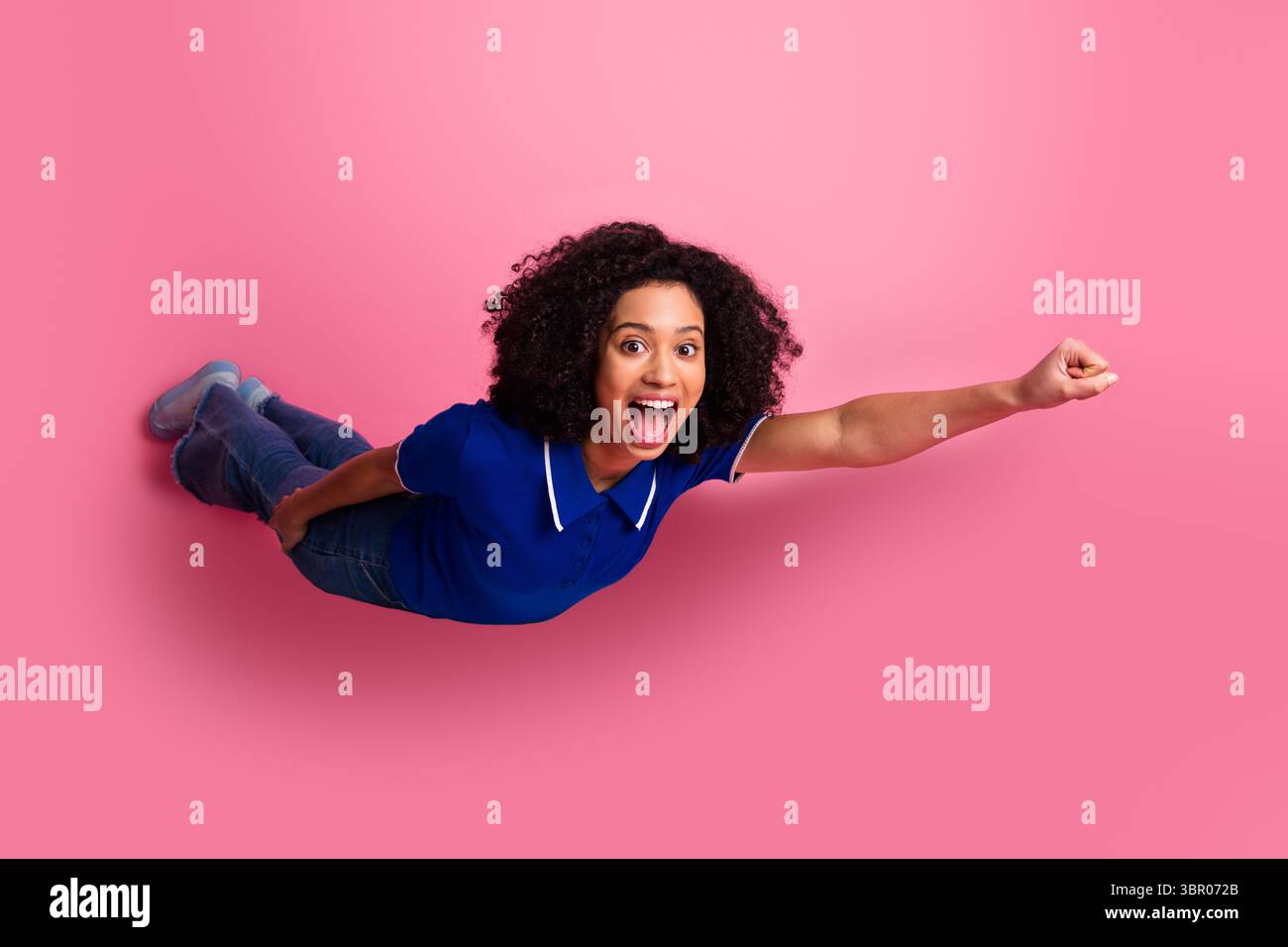 Energetic young woman with curly hair in casual attire mimicking a ...