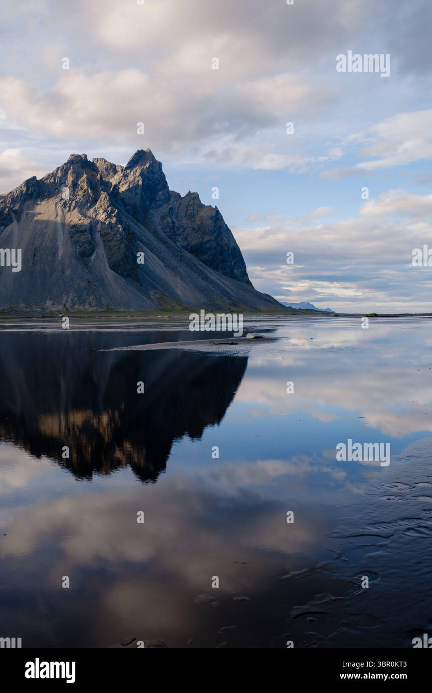 Tranquil waters mirror a stunning mountain in Iceland, where dramatic ...