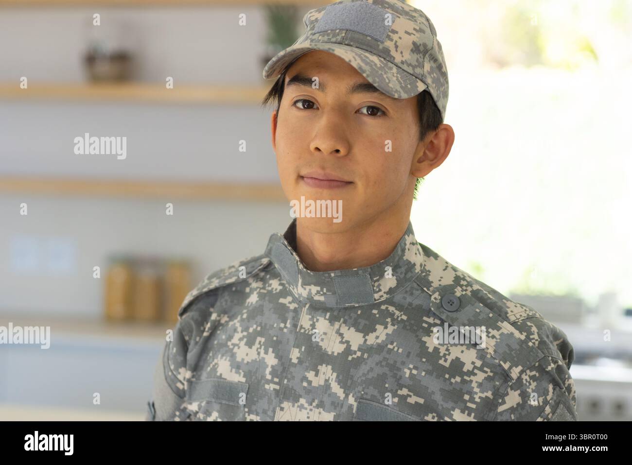 Asian male soldier standing in kitchen by shelves with jars wearing ...
