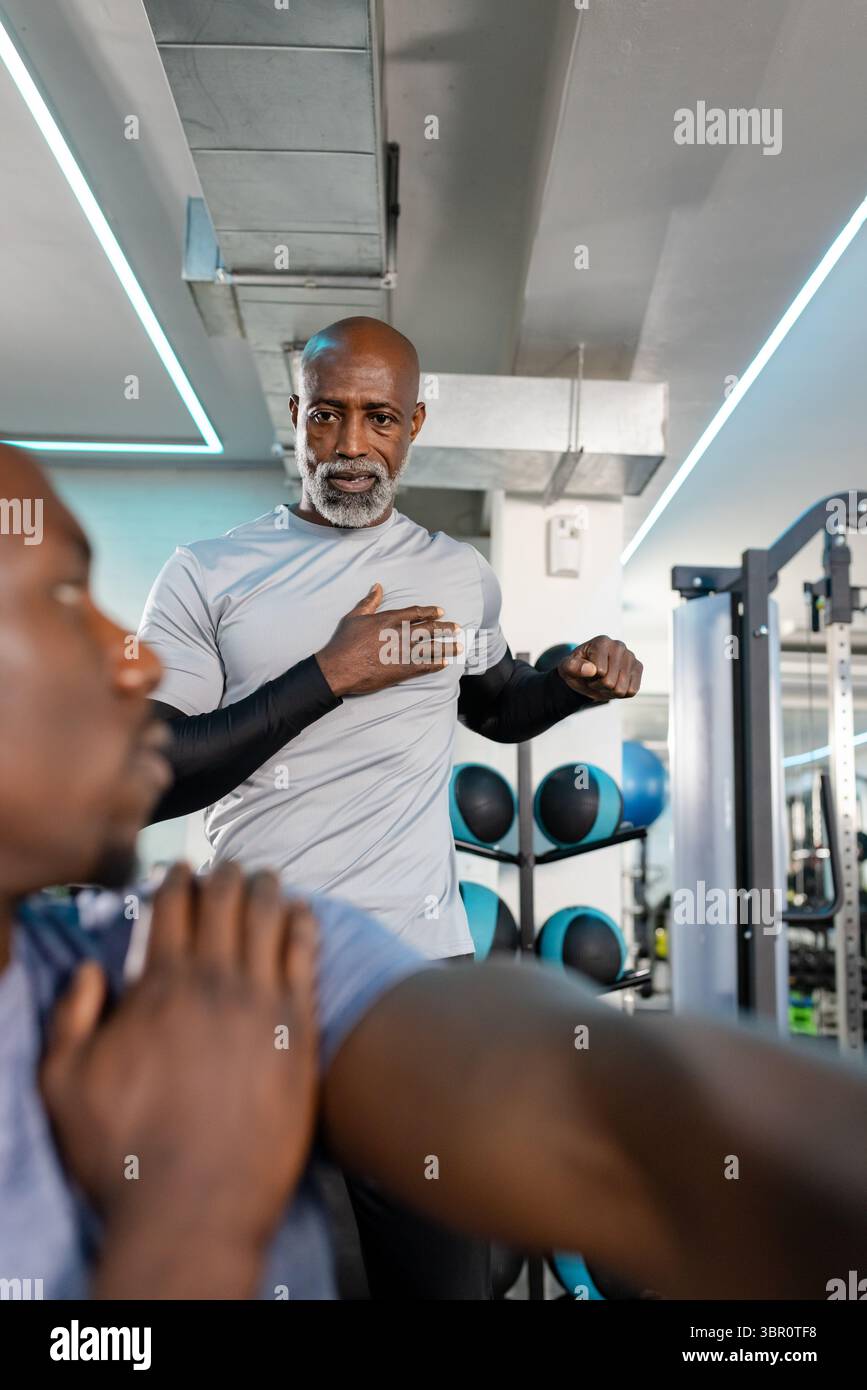 African American male trainer and client performing chest stretch at ...