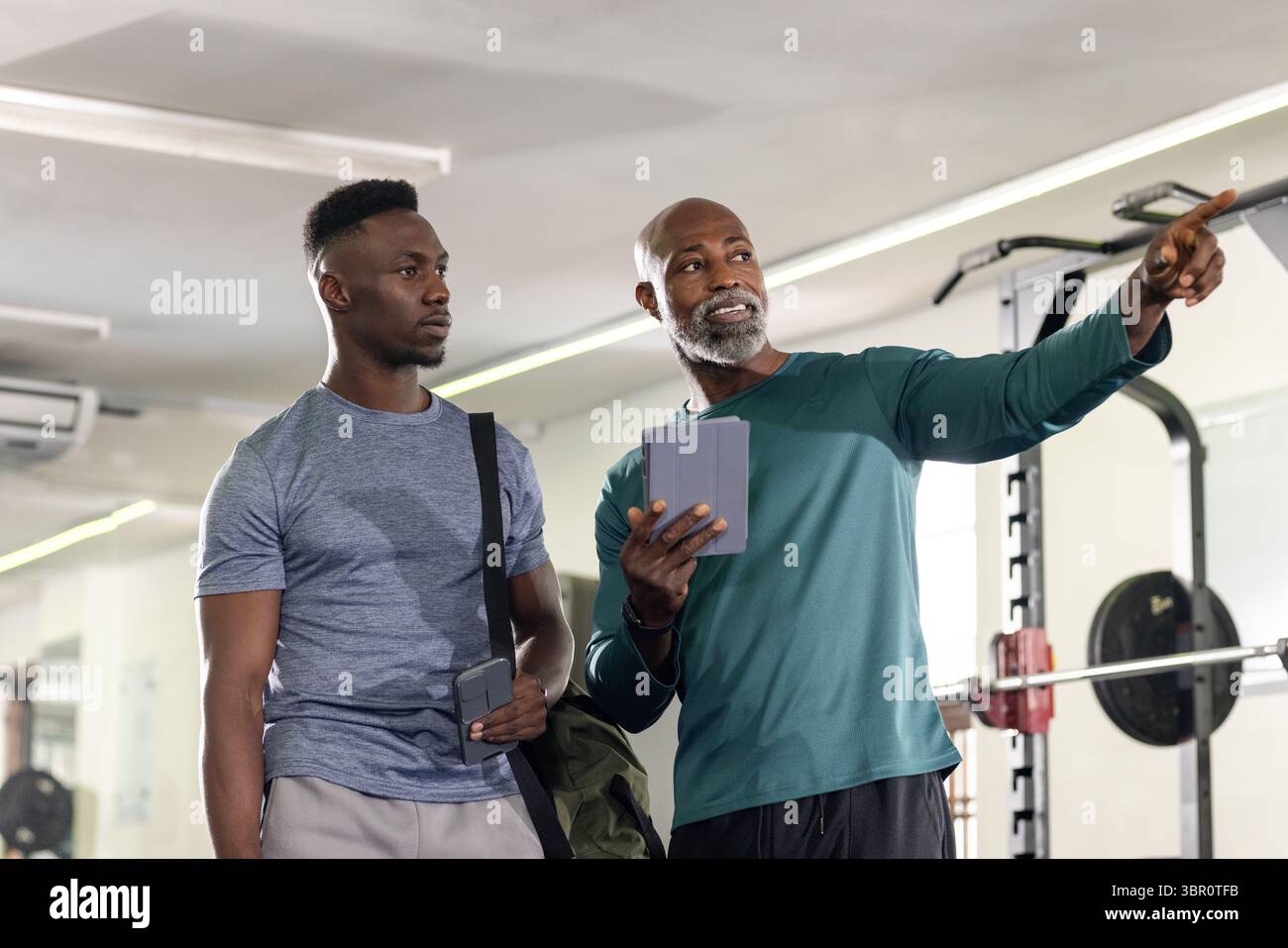 African American men demonstrating exercise technique at gym weight ...