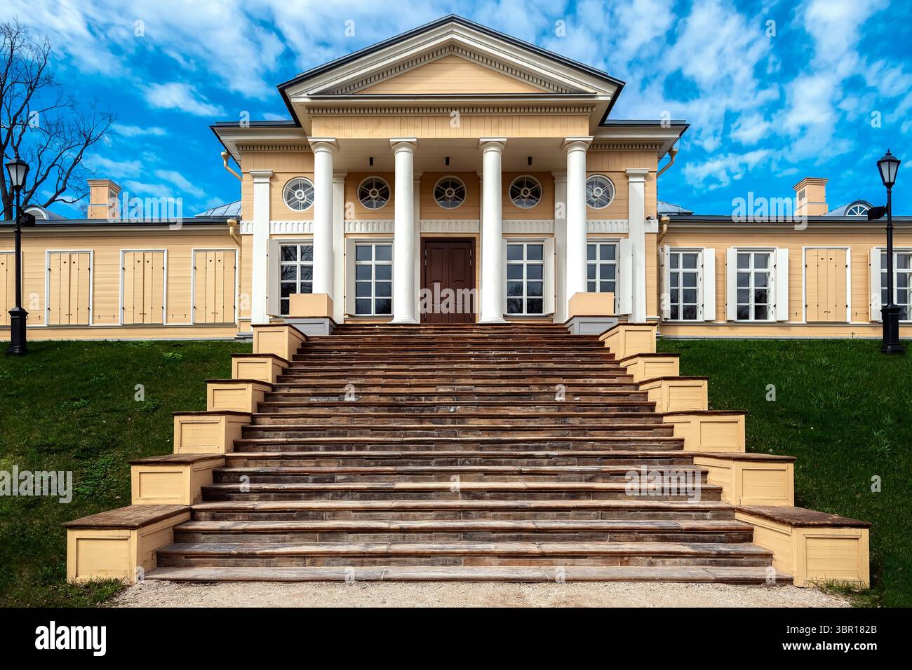 Wooden house with white columns and a wide staircase with stone steps ...