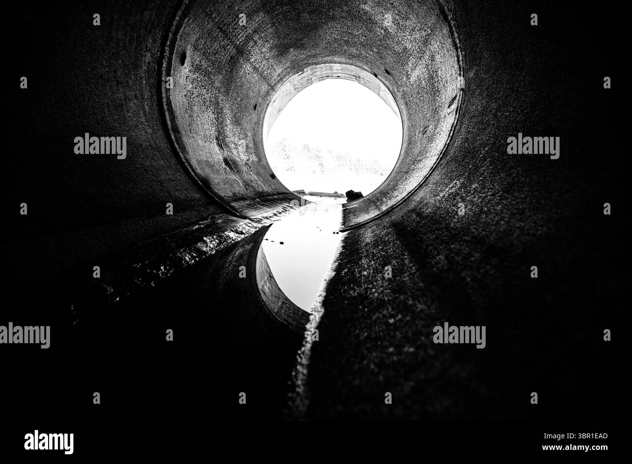 Inside a circular concrete drainage culvert with a trickle of water ...