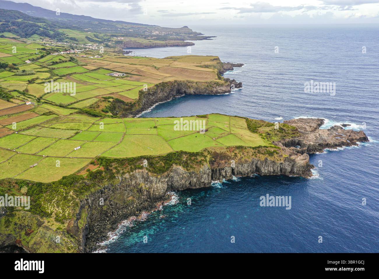 Aerial view of the rugged coastline where verdant fields meet the deep ...