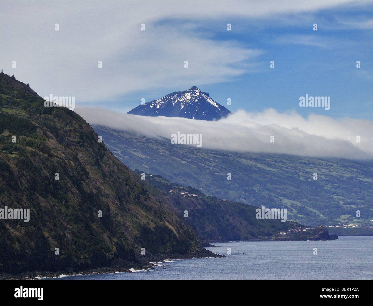 Aerial view of a majestic, snow-capped mountain peak piercing through a ...