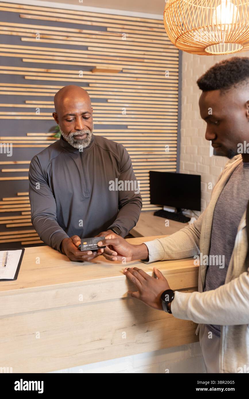 African American senior receptionist exchanging credit card with ...