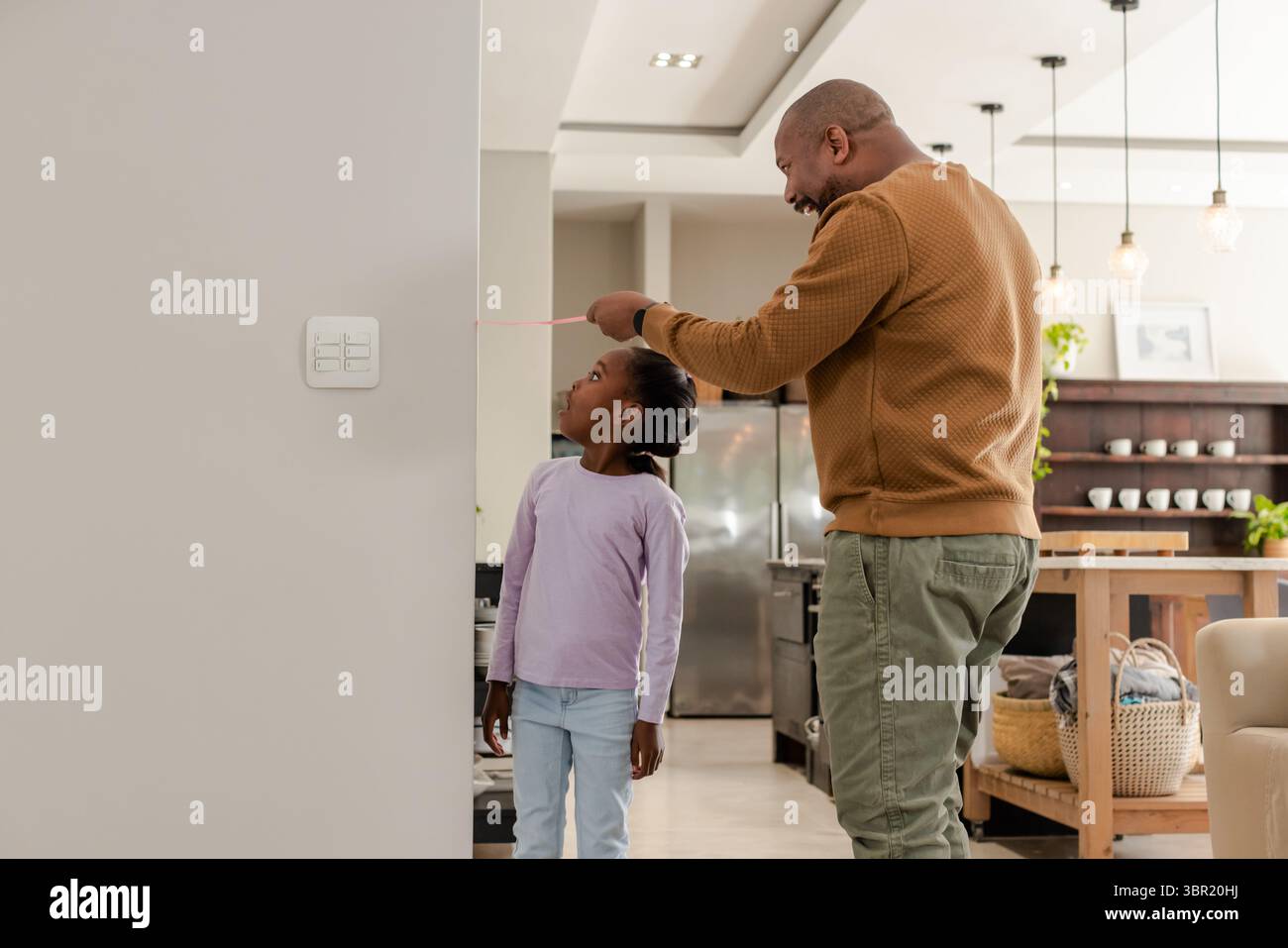 African American parent and child measuring height with tape measure ...