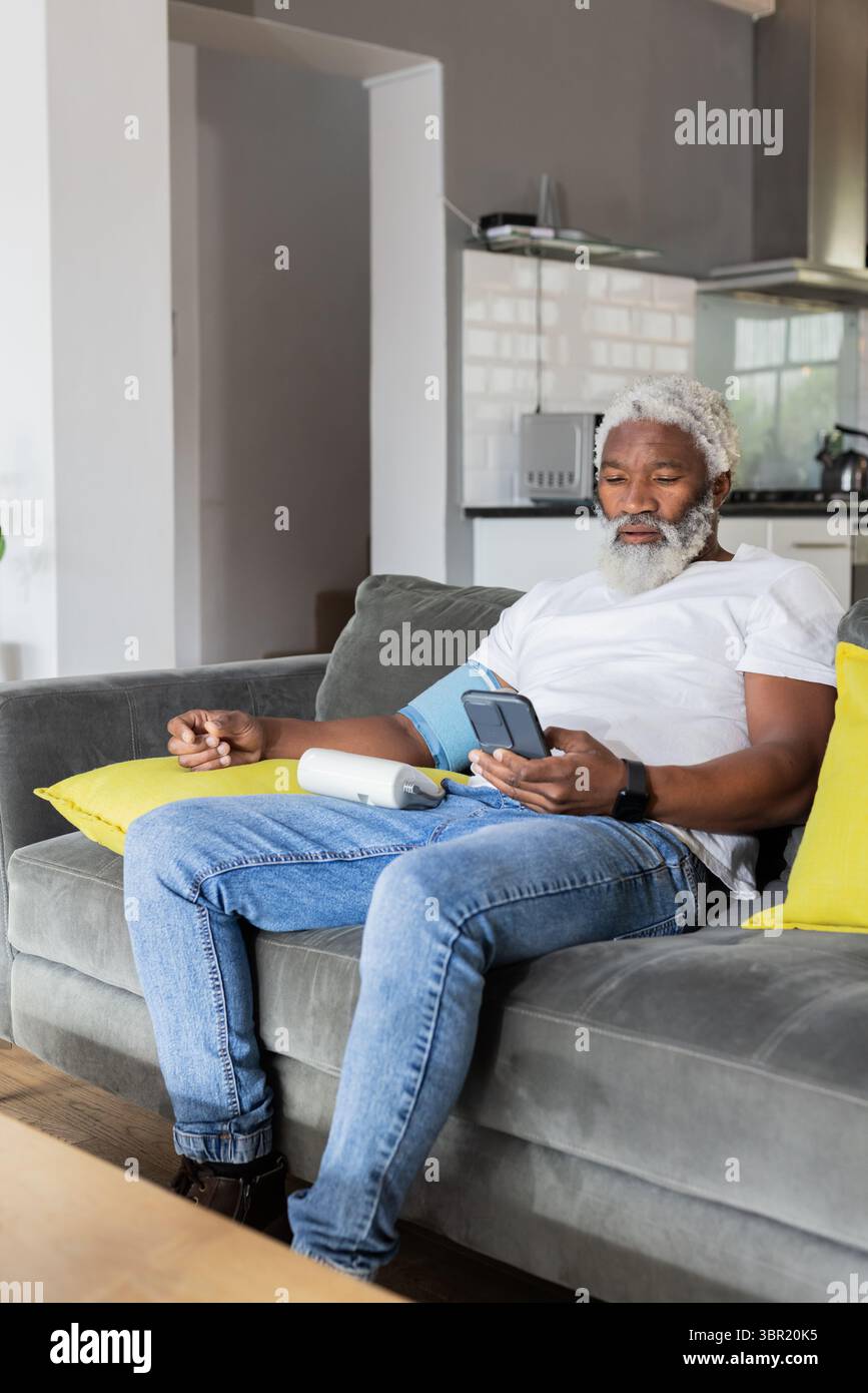 Senior African American man checking smartphone, taking blood pressure ...