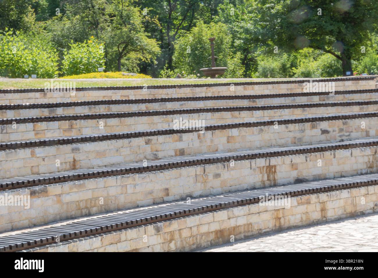 Stone amphitheater seating with wooden benches in public park on a ...