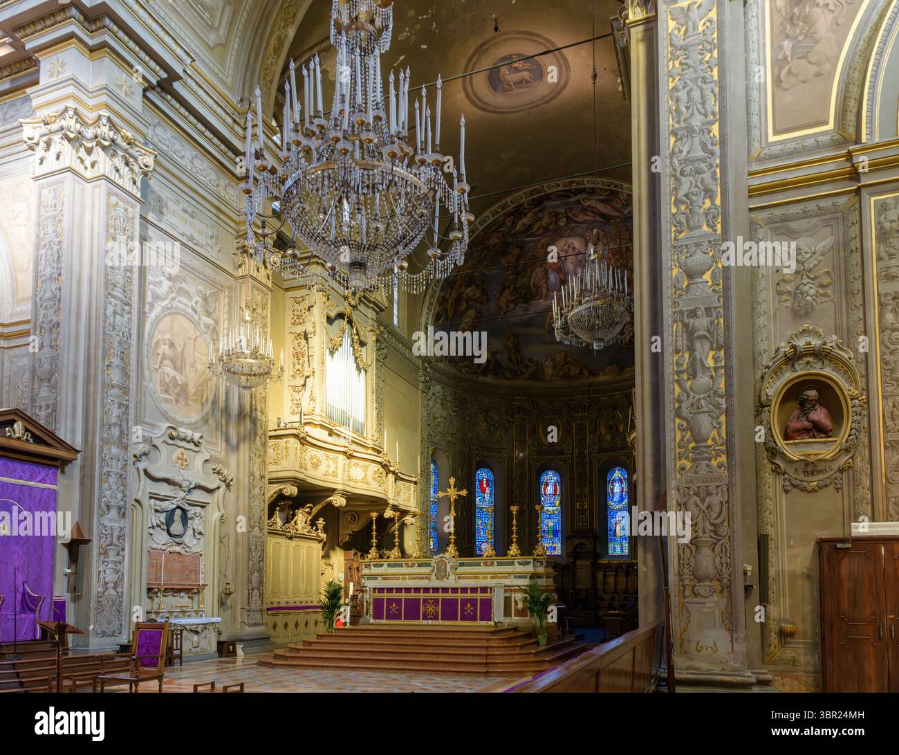 Baroque church interior with frescoed apse, chandeliers, pews, and ...
