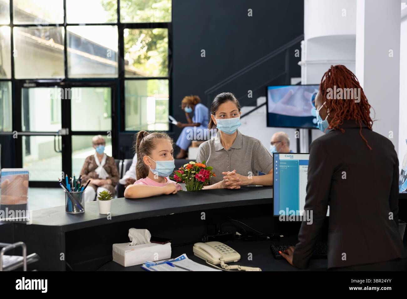 Receptionist greeting mother and child at the hospital front desk ...