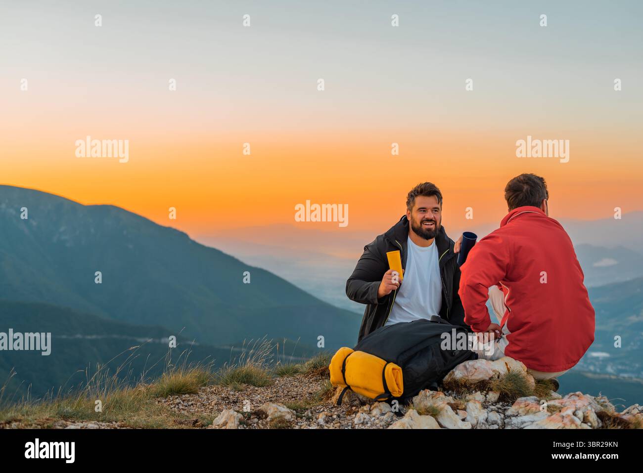 Two friends travelers enjoys while drinking a cup of coffee at the top ...