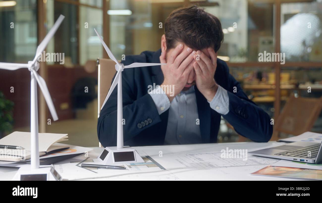 Disappointed Caucasian businessman looking wind turbine models sighing ...