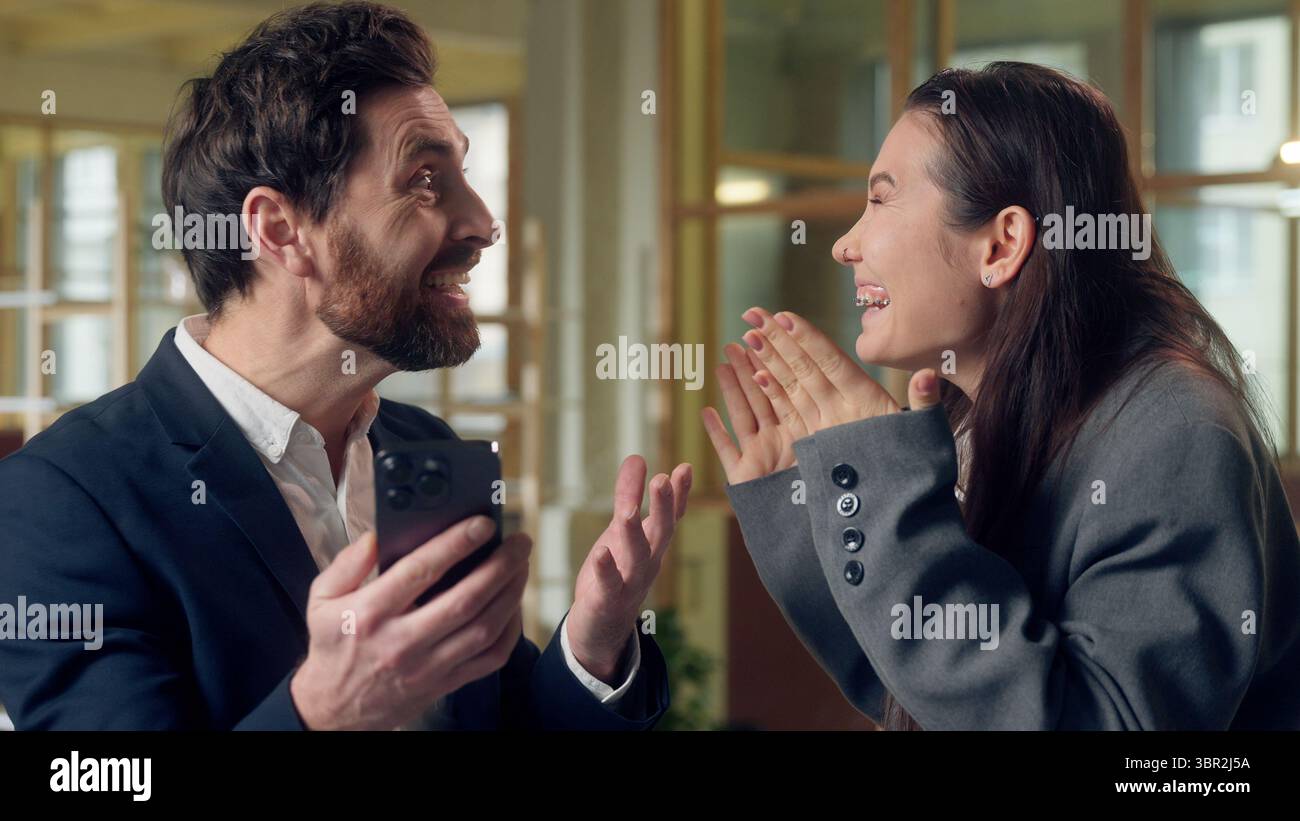 Excited shocked Caucasian Korean business man woman using mobile phone ...