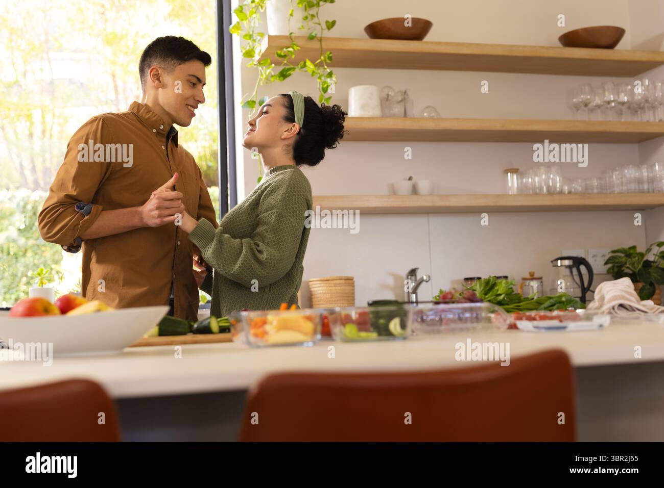 Couple dancing and holding hands on kitchen island near white fruit ...