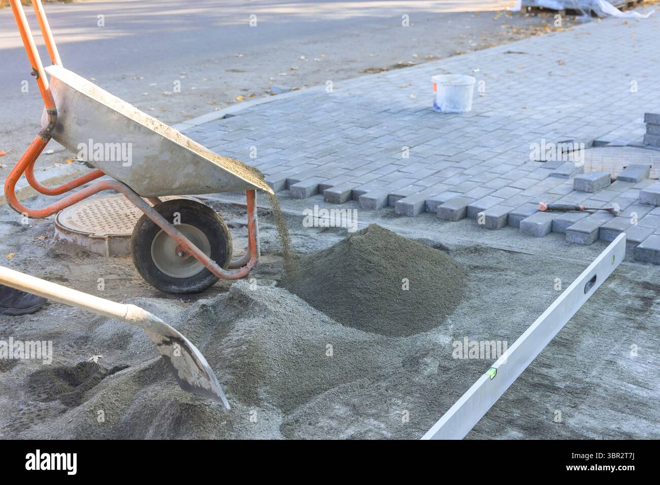 Workers are preparing to install pavers on street using wheelbarrow for ...