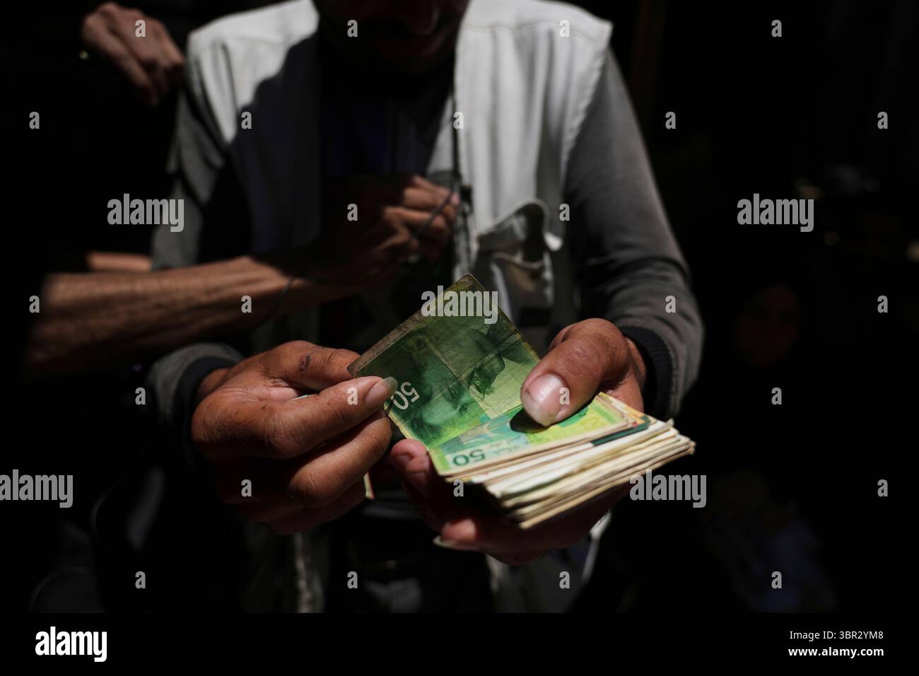 A Palestinian vegetable merchant shows worn-out Israeli currency ...