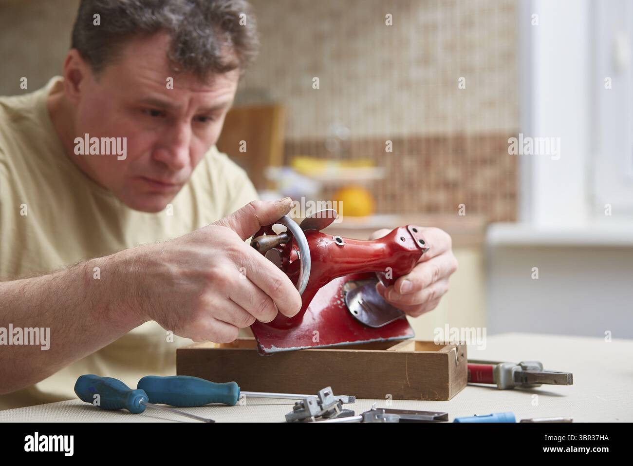 Male master repairs the sewing machine. Inspection of the mechanism in ...
