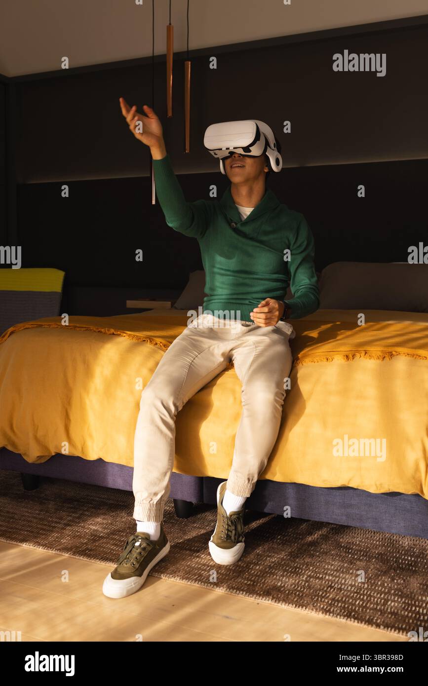 Man is sitting on mustard blanket bed using VR headset with pendant ...