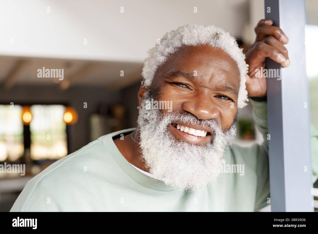 Smiling Senior African American man leaning against post in open plan ...