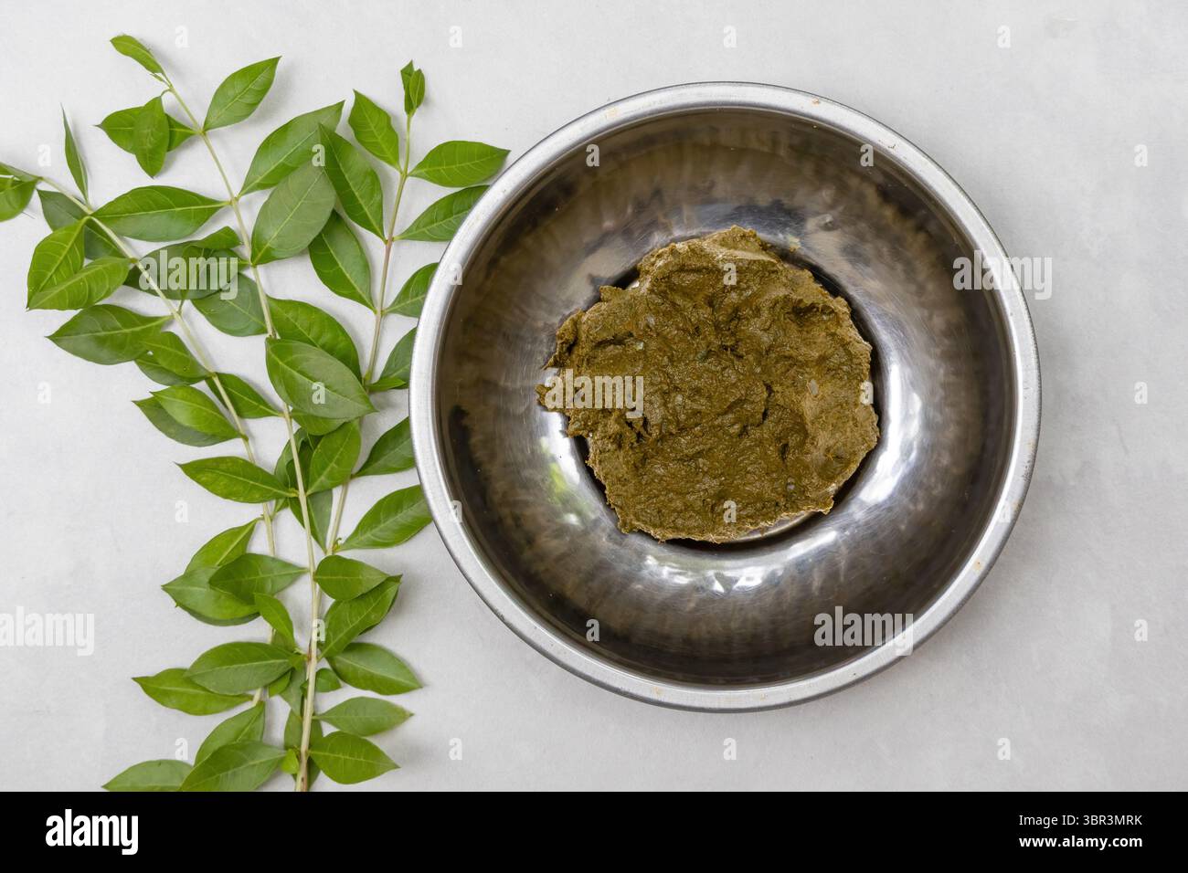 Top view of vibrant green Henna paste in a steel bowl, accompanied by ...