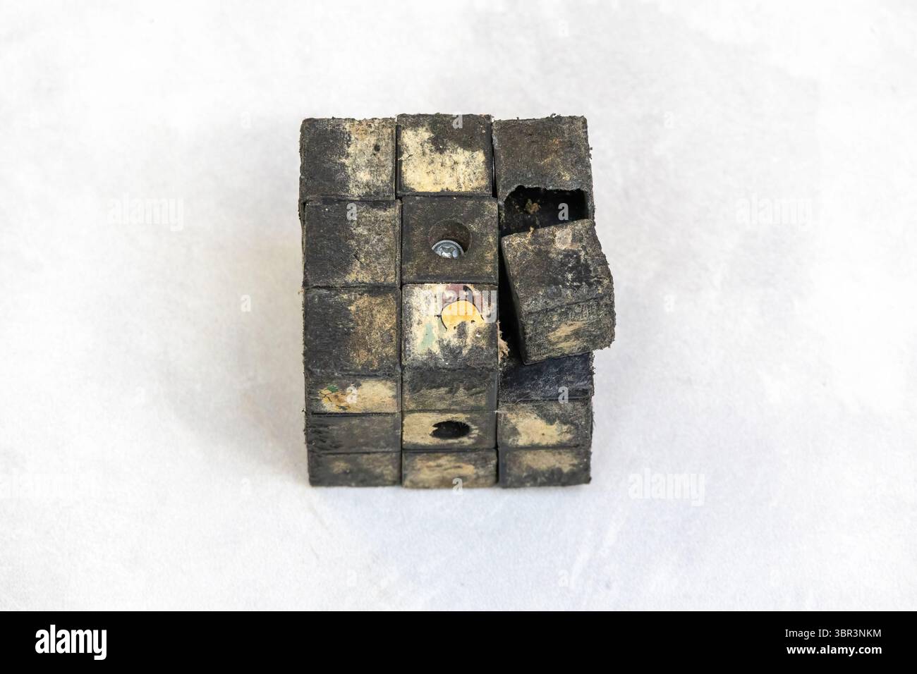 A broken and damaged old Rubik's Cube toy, close-up with visible cracks ...