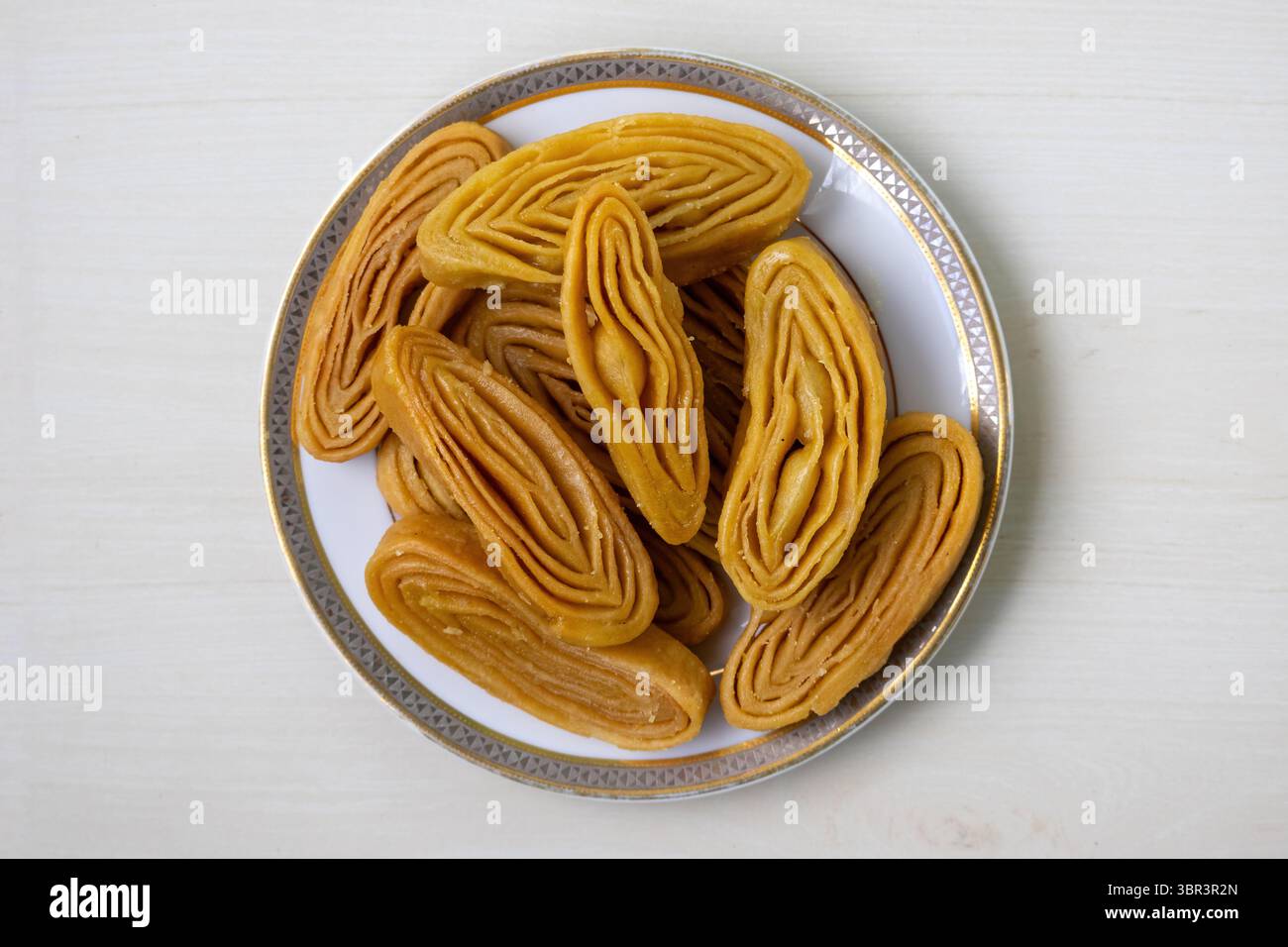 Gaja sweet on white plate, wooden background. Also known as Khaja ...