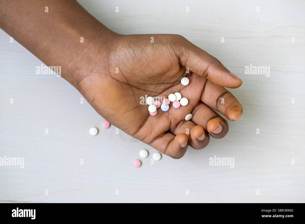 Top view of a female hand with numerous pills lying on the floor. This ...