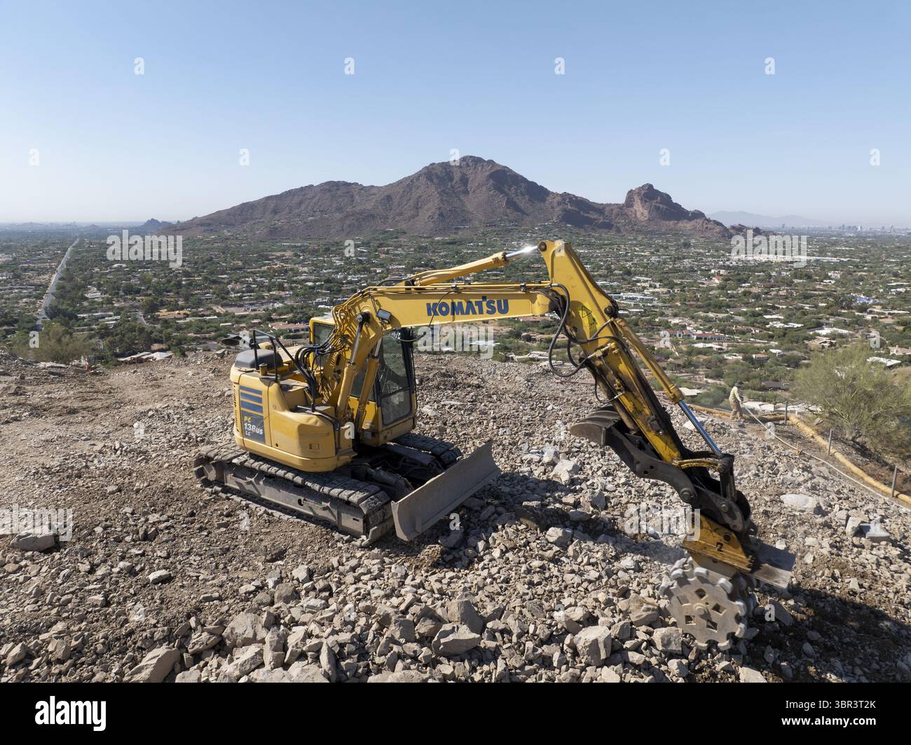 Aerial view of a bright yellow Komatsu excavator poised on a rocky ...