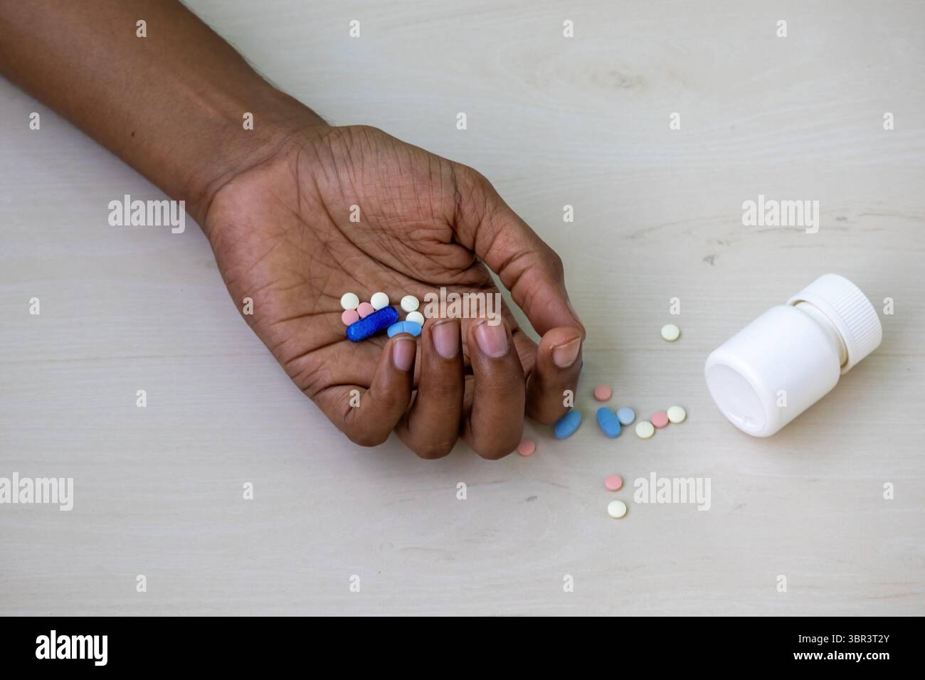 Close-up hand holds diverse tablets and pills. Spilled bottle ...