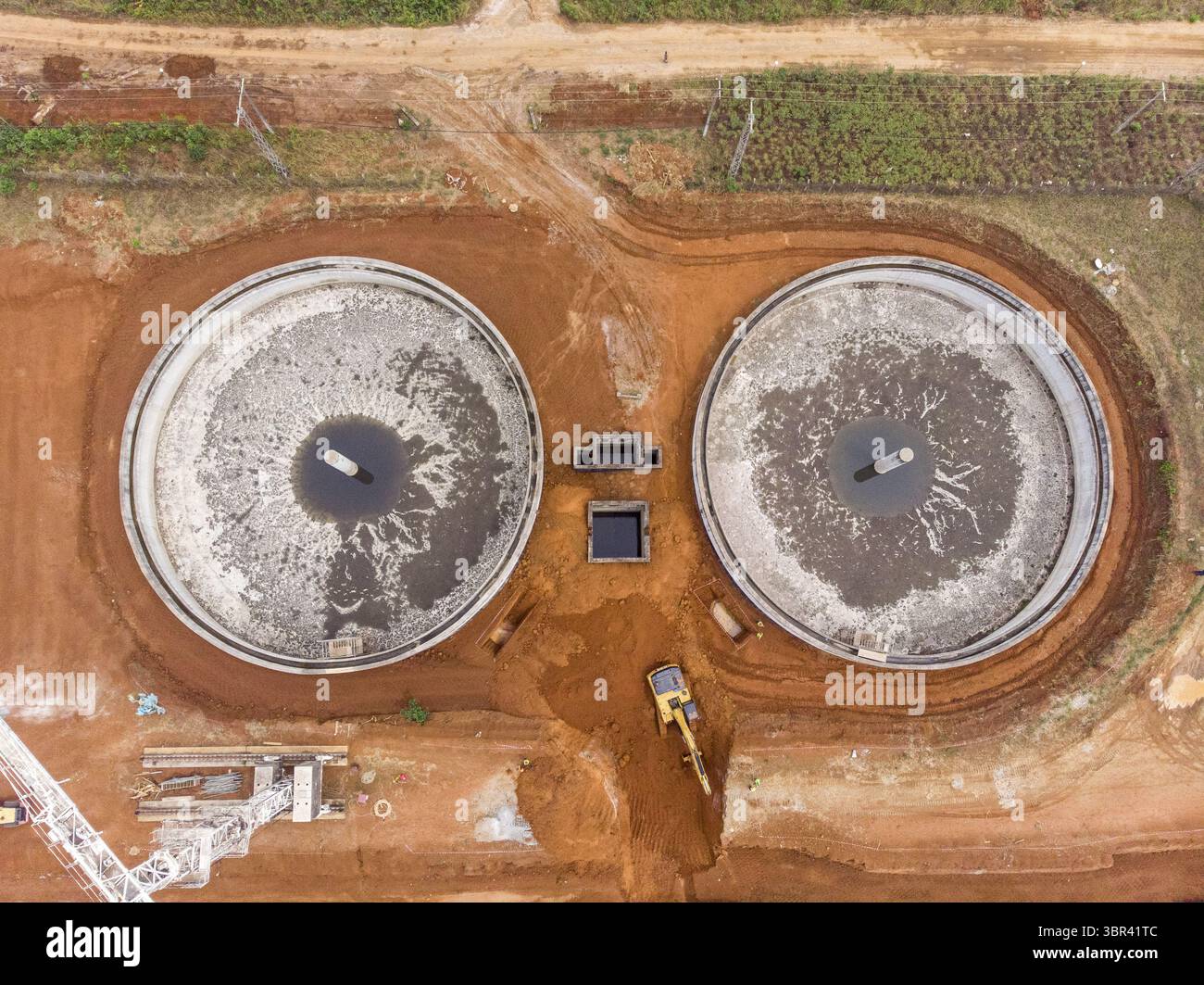 Aerial view of two large circular tanks under construction surrounded ...