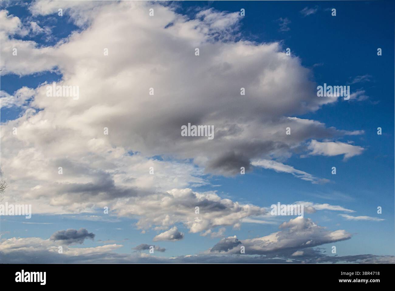 Fluffy clouds float amidst a brilliant blue sky showcasing a blend of ...