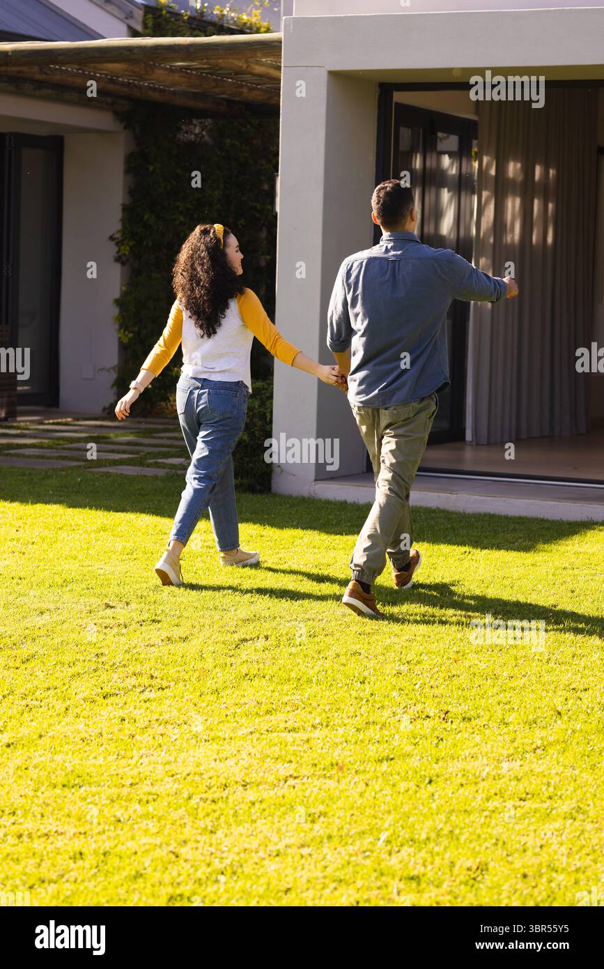 Couple walking hand in hand across stepping stones in yard toward ...