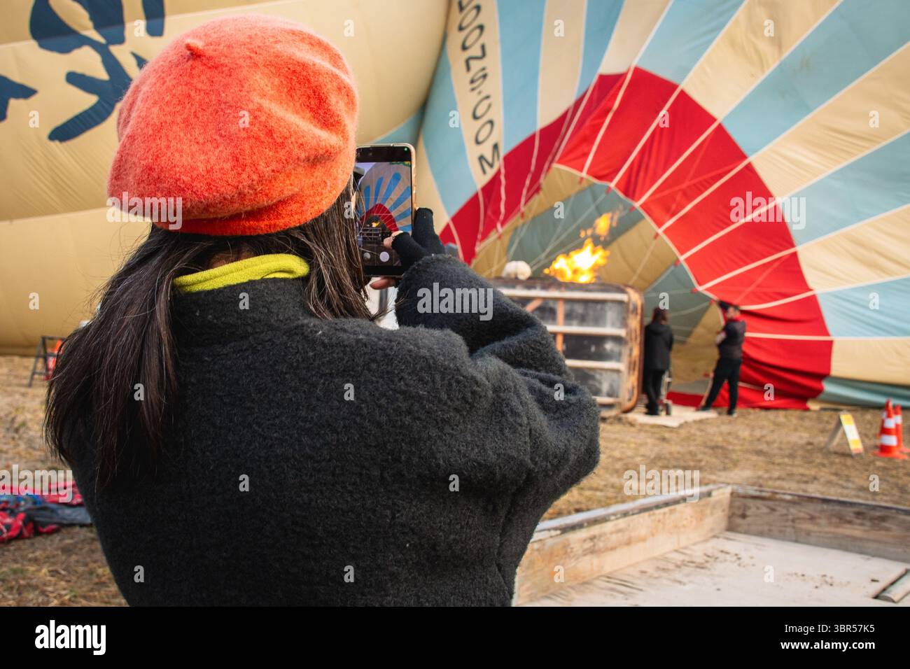 Back view woman in red beret capturing smartphone photo of colorful hot ...