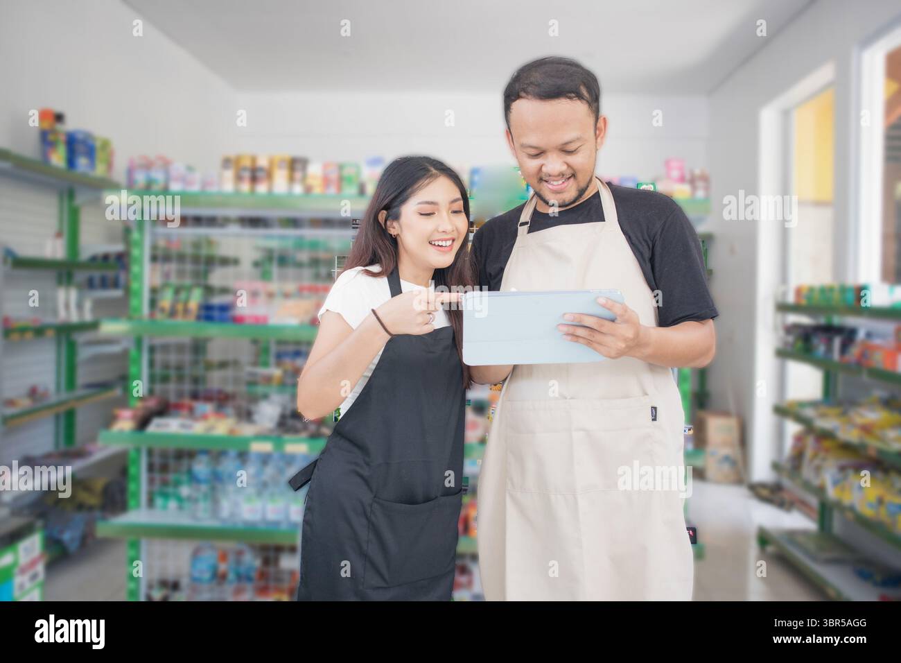 friendly Asian Cashier couple discussing pointing tab, cashier wearing ...