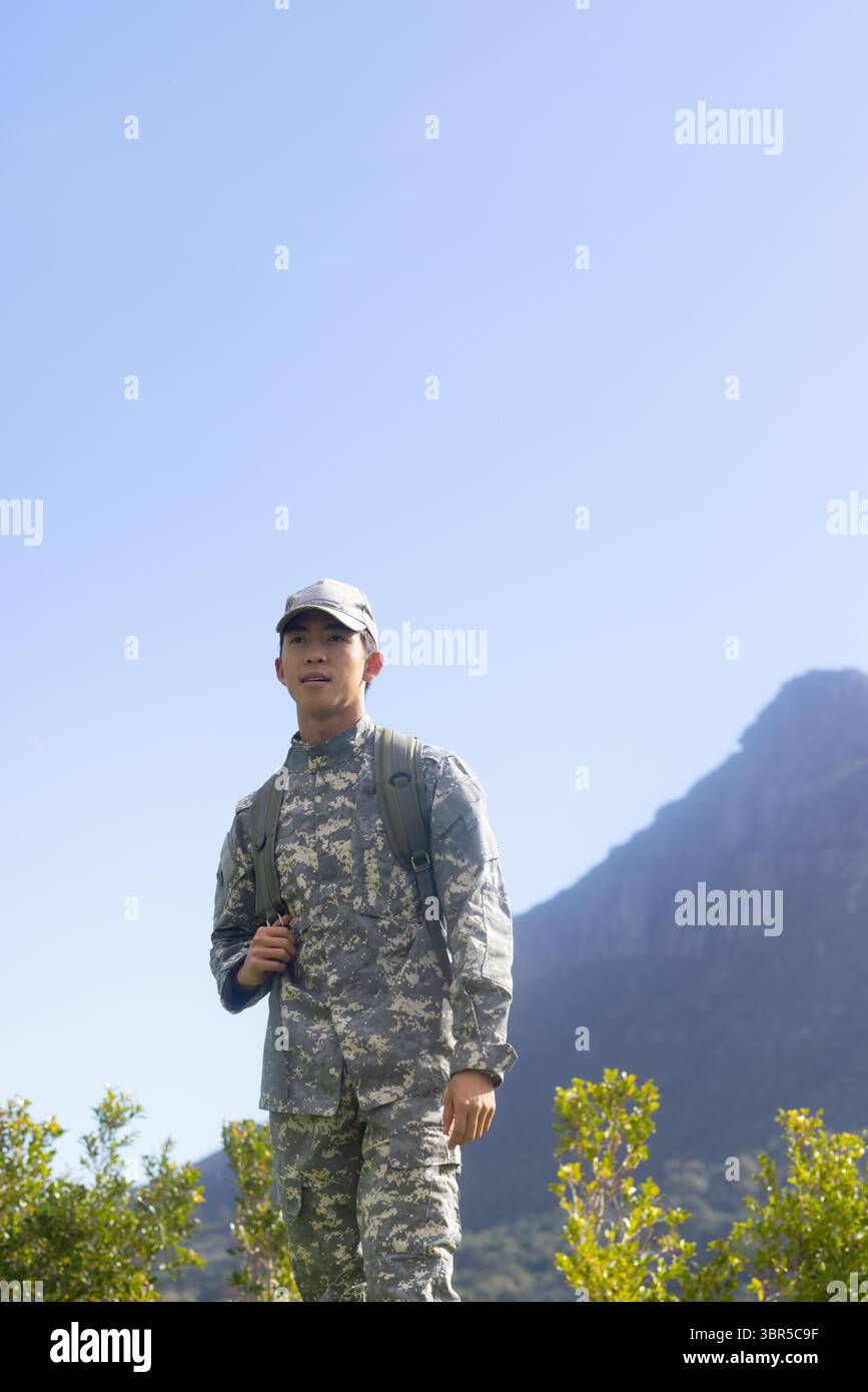 Asian male soldier standing in camo uniform and cap, carrying tactical ...