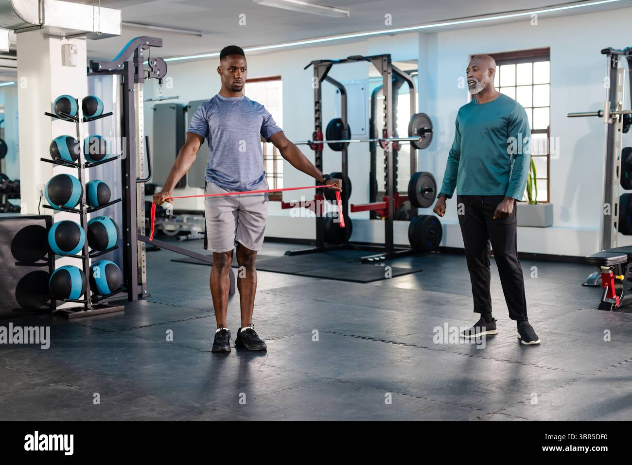 African American trainer and client performing resistance band exercise ...
