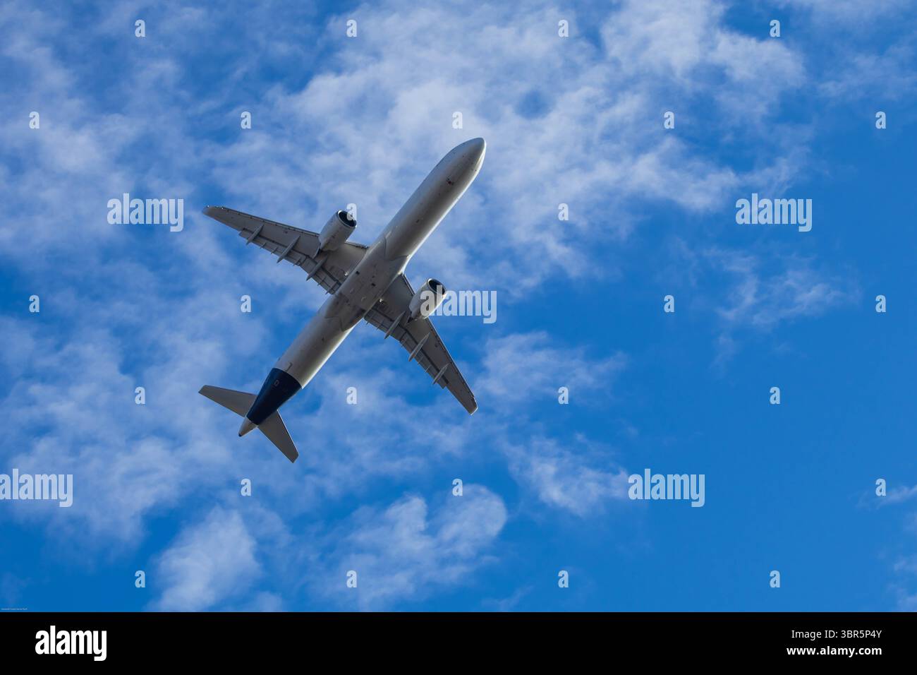 White passenger airplane soaring high in a partly cloudy sky, captured ...