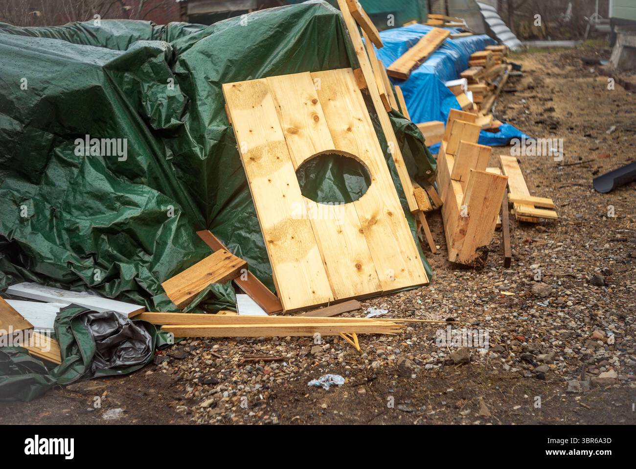 a wooden seat of a countryside toilet abandoned in a messy backyard ...