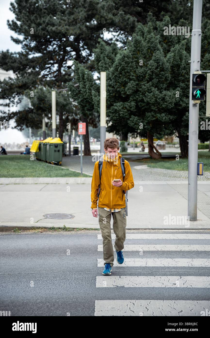 Man crossing street at green pedestrian light with smartphone Stock ...