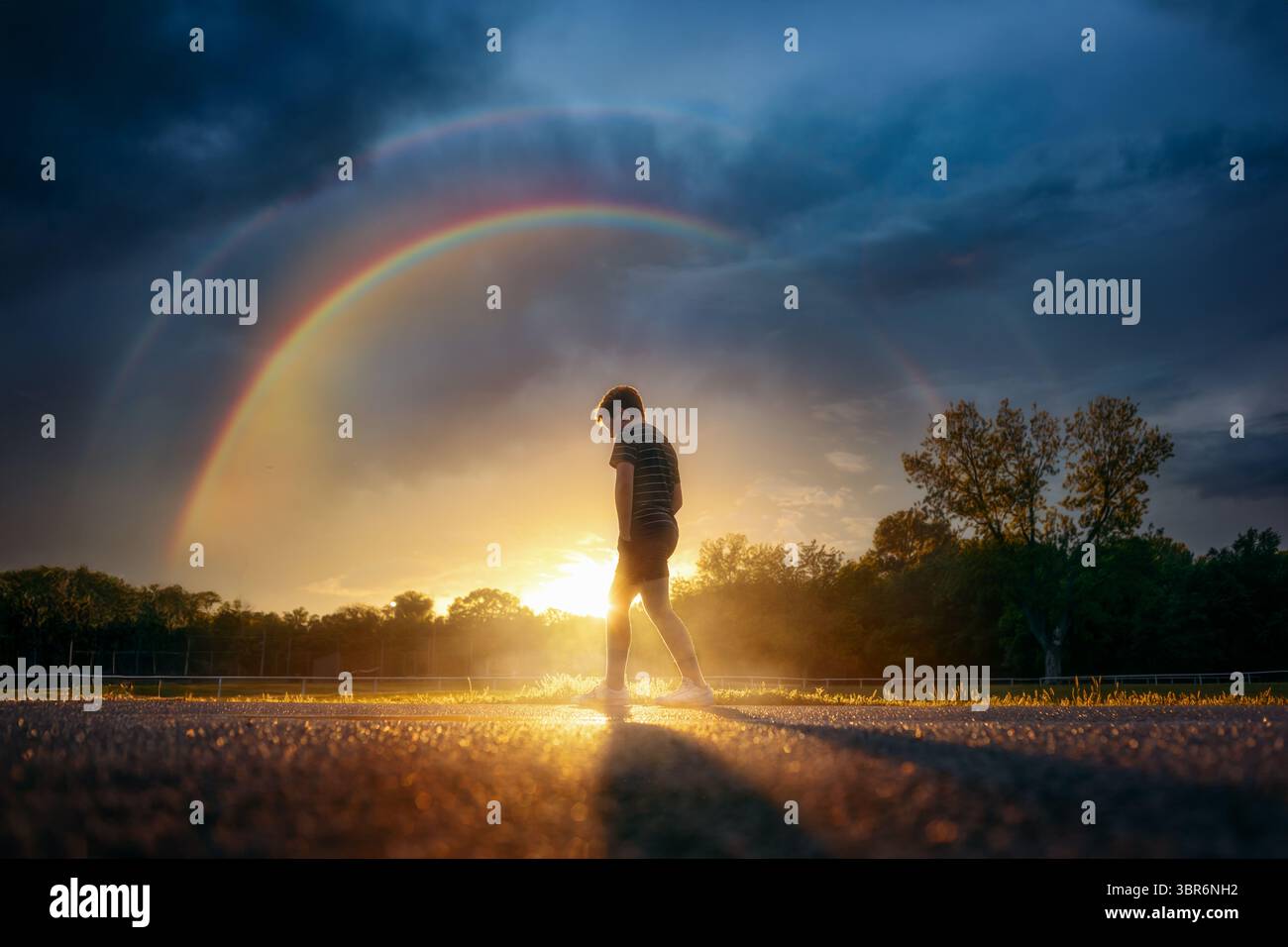Pre-teen Boy Walking Under Storm Clouds with Rainbow Stock Photo - Alamy