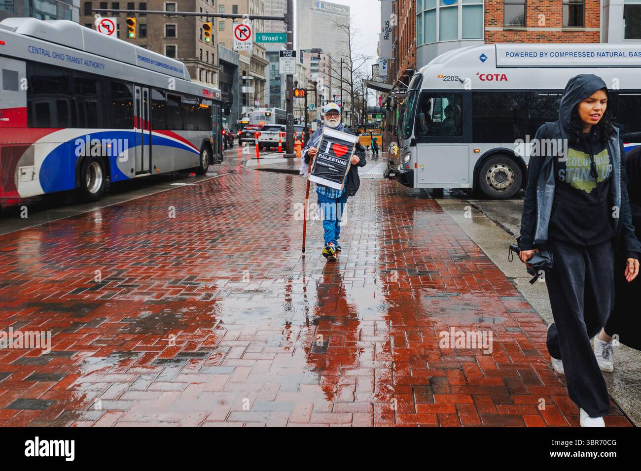Man walks through city street in rain with Palestine protest sign Stock ...