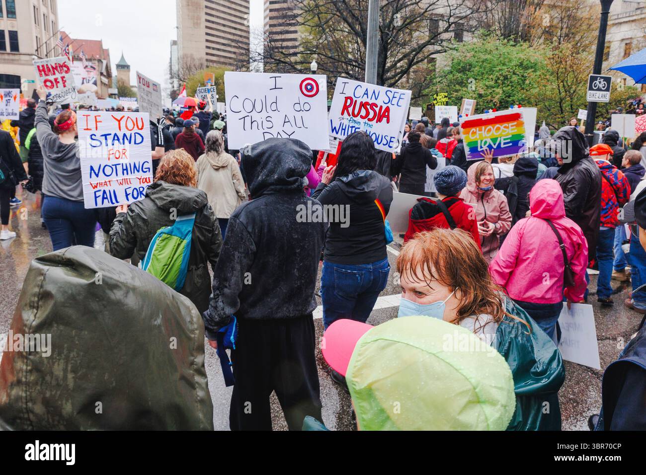 A crowd holds protest signs in large rally in rain Stock Photo - Alamy
