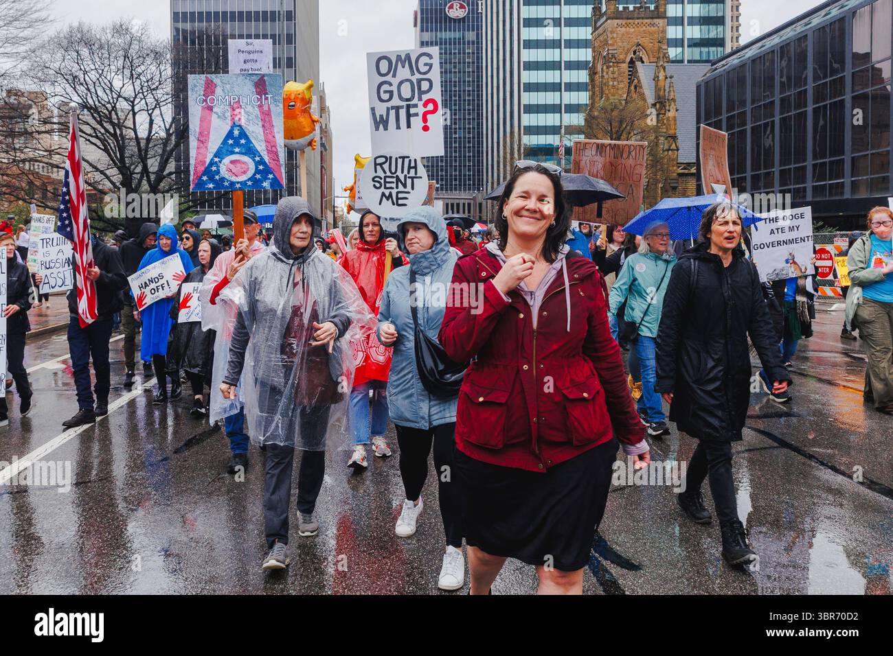 A smiling woman leads a crowd marching in protest with signs Stock ...