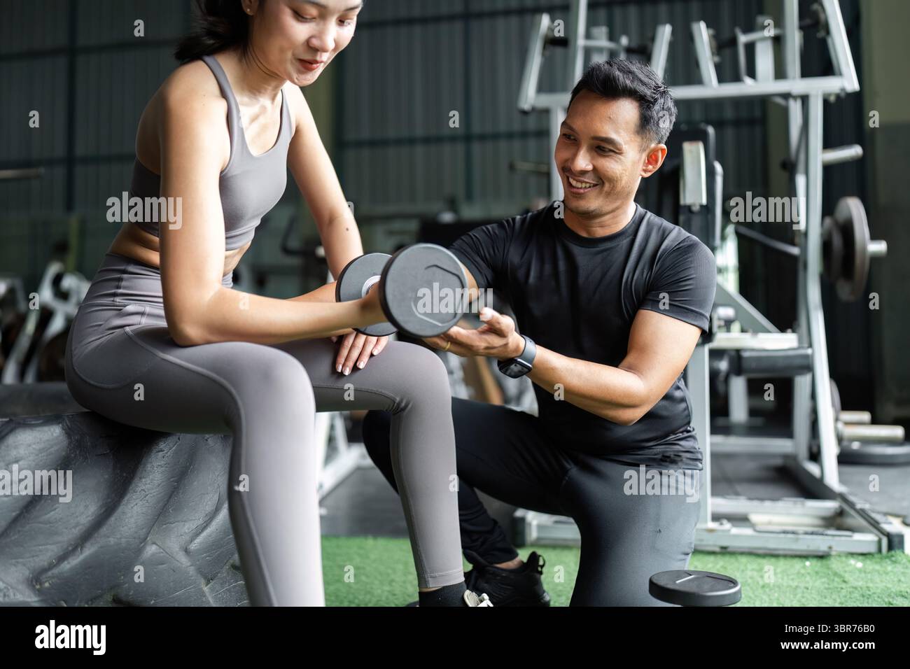 Personal Trainer Assisting Female Client with Dumbbell Exercise. Focus ...