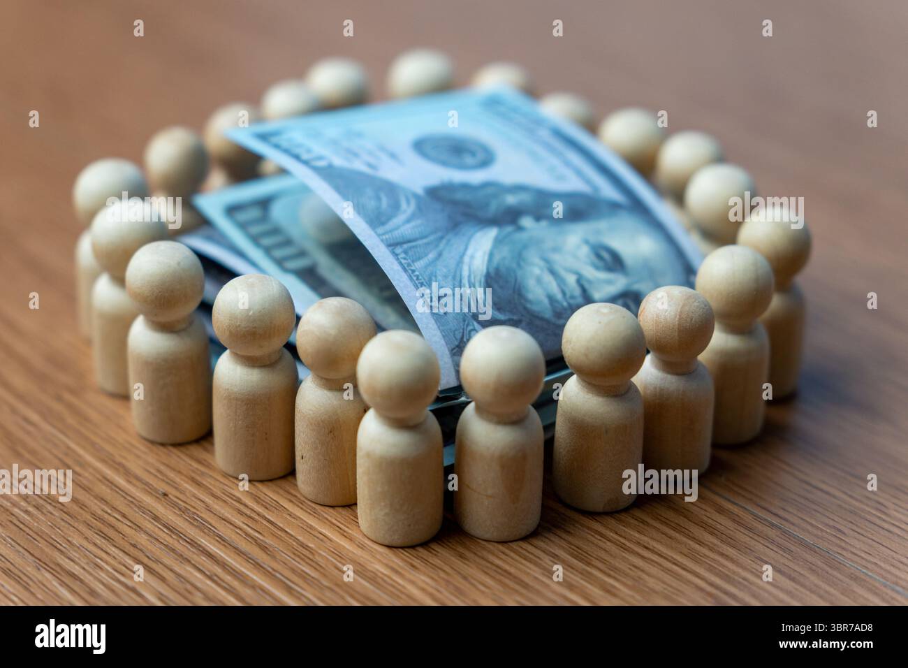 A stack of U.S. hundred-dollar bills surrounded by a wooden human ...
