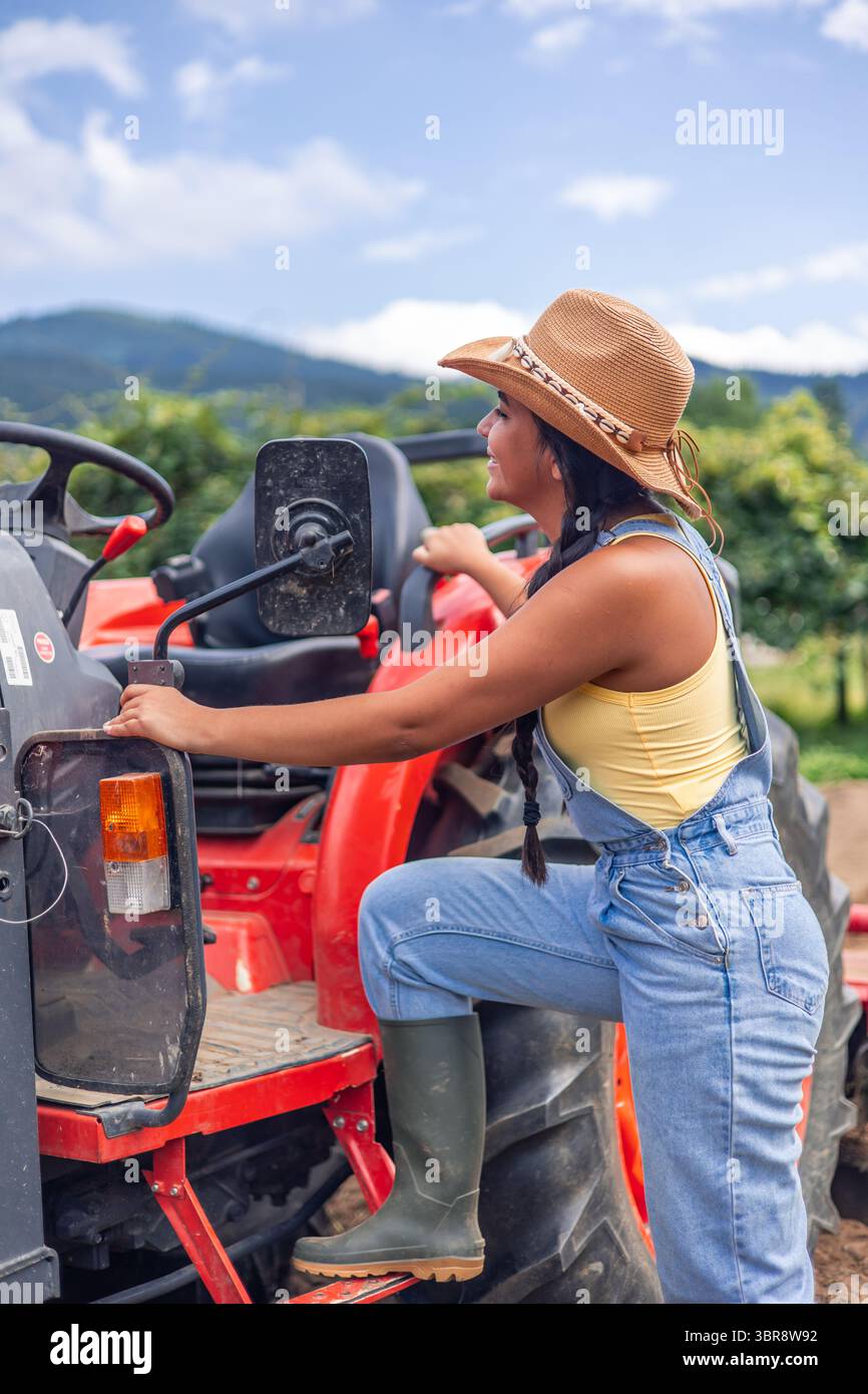 vertical Young latin american female farmer with straw hat and denim ...