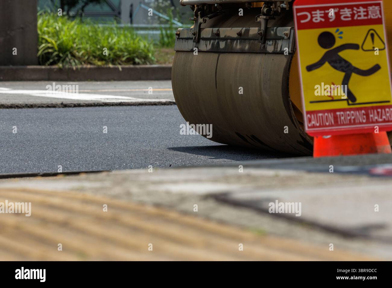 Mini tandem roller machine's front roller appears behind sign ...
